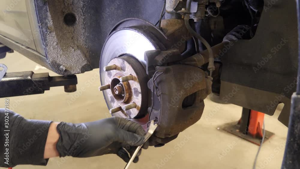 Mechanic removes the caliper pin on the disc brake component of a car ...