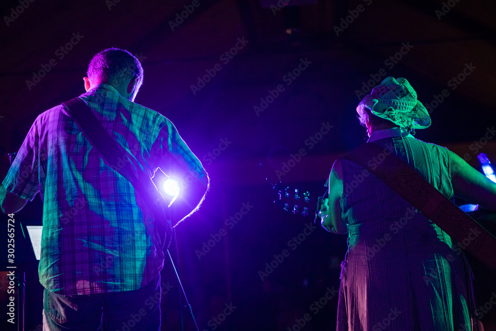 Behind view photo of two musicians playing their instruments on stage ...