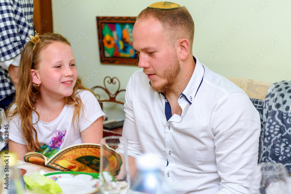 Jewish family celebrate Passover Seder reading the Haggadah. Stock ...