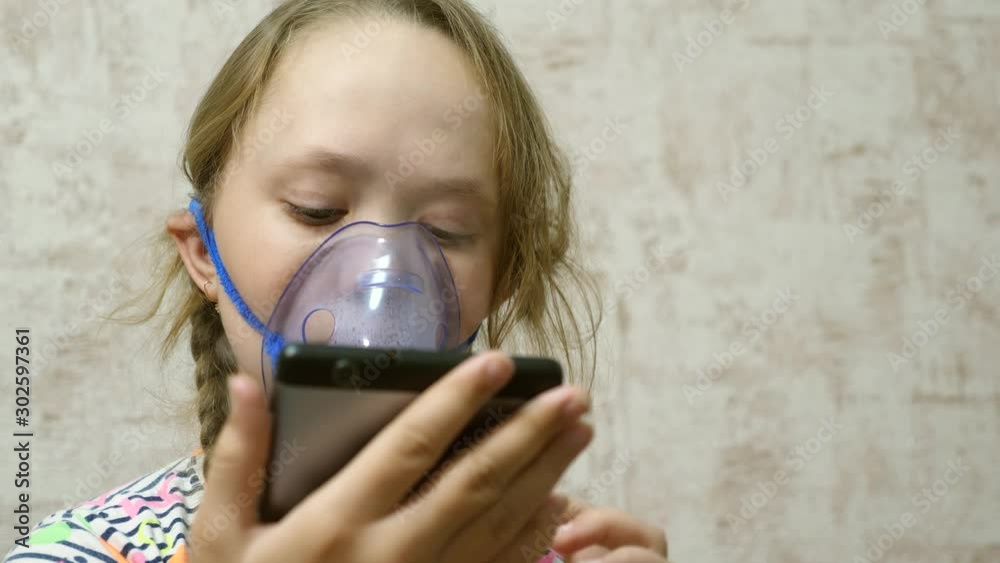 child with a tablet is sick and breathes through an inhaler. close-up ...