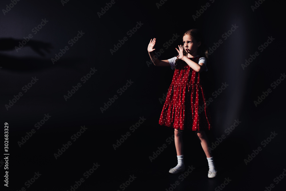 scared child standing in darkness with outstretched hands on black ...