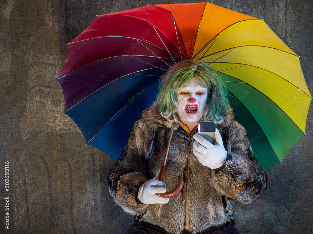 Crazy aggressive clown with smartphone umbrella. man hates his work and ...