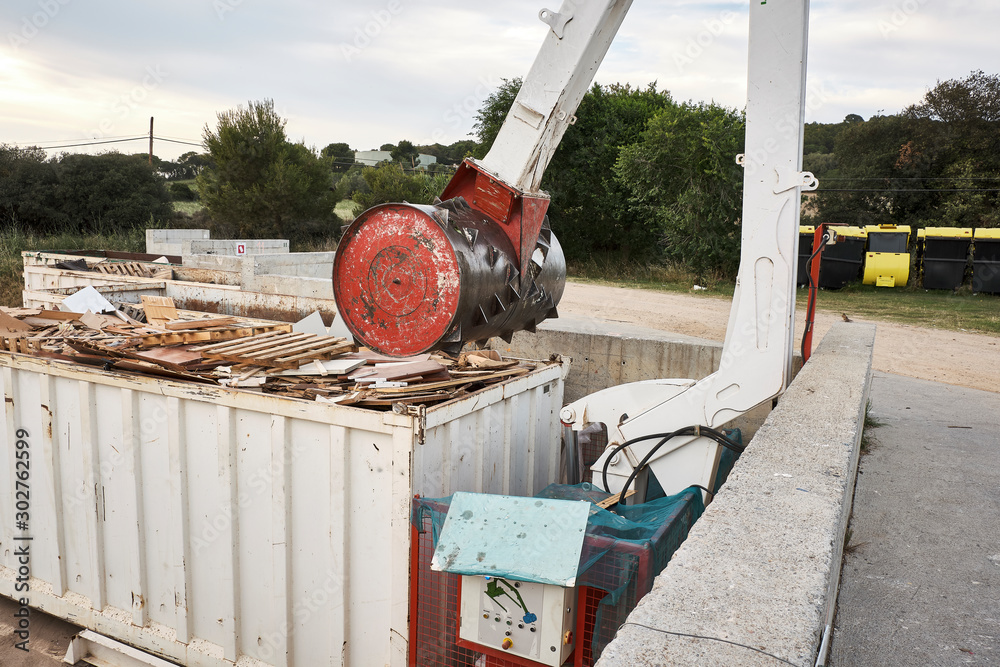 Waste garbage compactor working on a dumpster bin in an outdoors ...