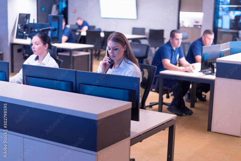 Group of security guards working on computers while sitting in the main ...
