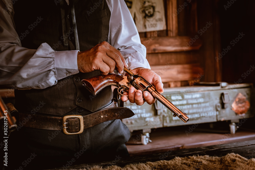 Closed up cowboy loading bullets into gun on hand before used to shot ...