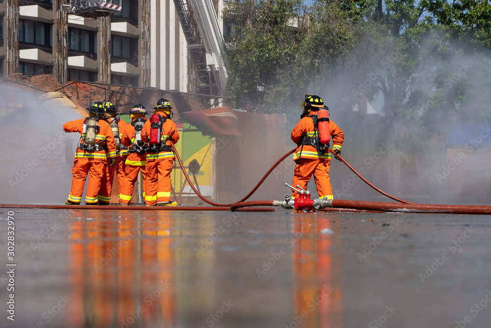 Brave firefighter using extinguisher and water from hose for fire ...