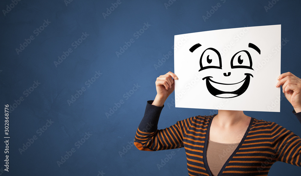 Casual person holding a paper in front of his face with drawn emoticon ...