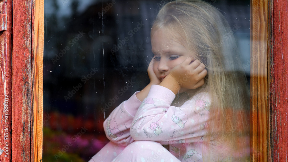 Little girl with a sad look. Sad baby by the window. Abandoned child by ...