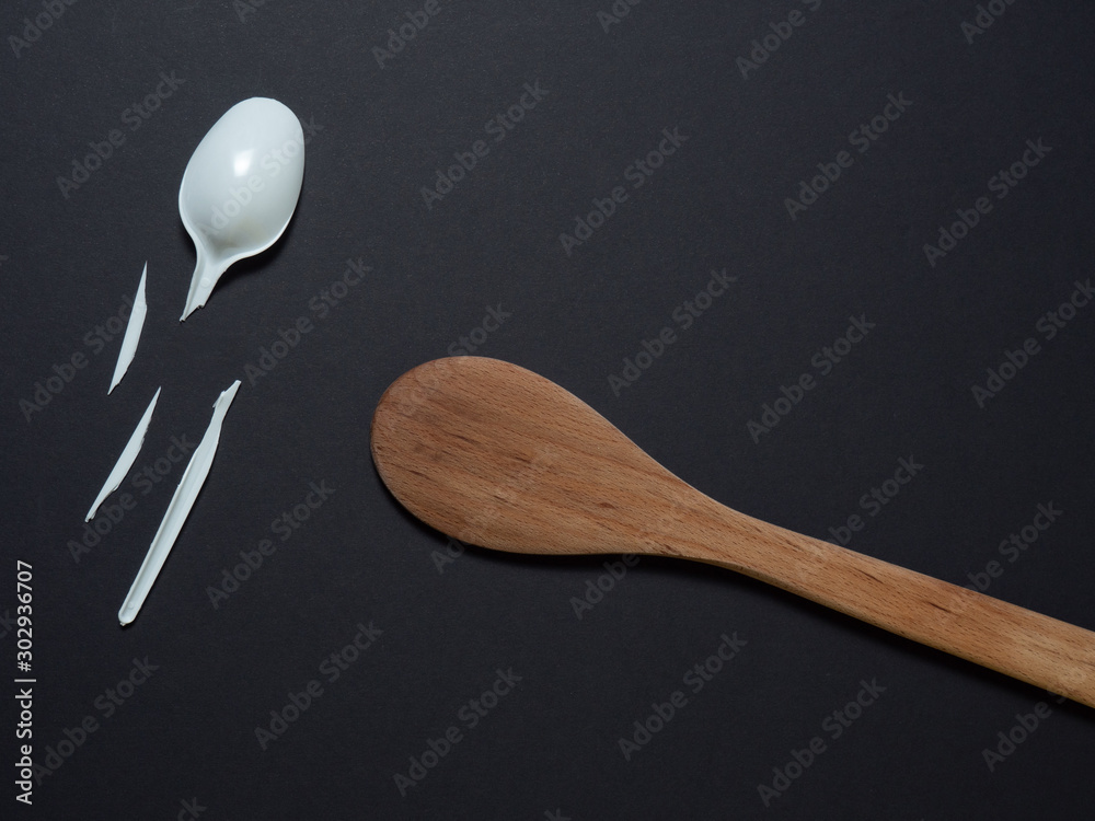 wooden spoon and a broken disposable spoon from a platik on a black ...