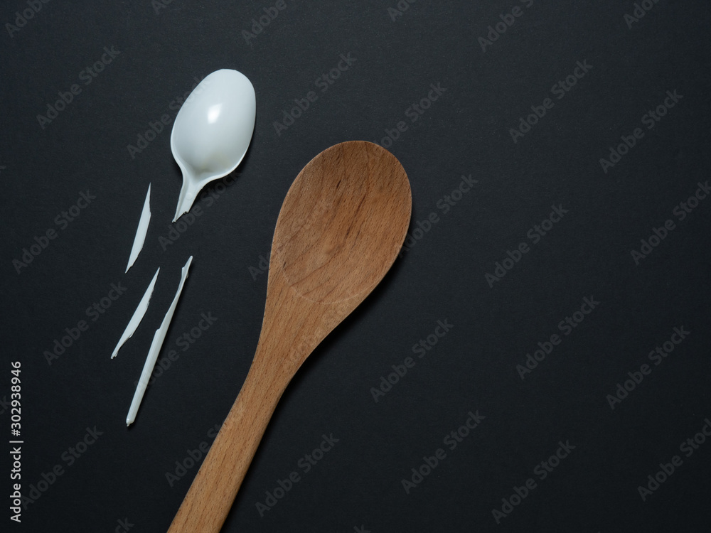 wooden spoon and a broken disposable spoon from a platik on a black ...