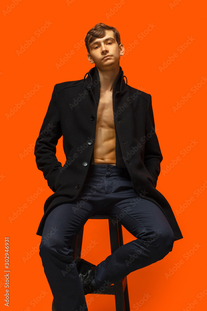 Portrait of a handsome young man isolated on orange studio background ...