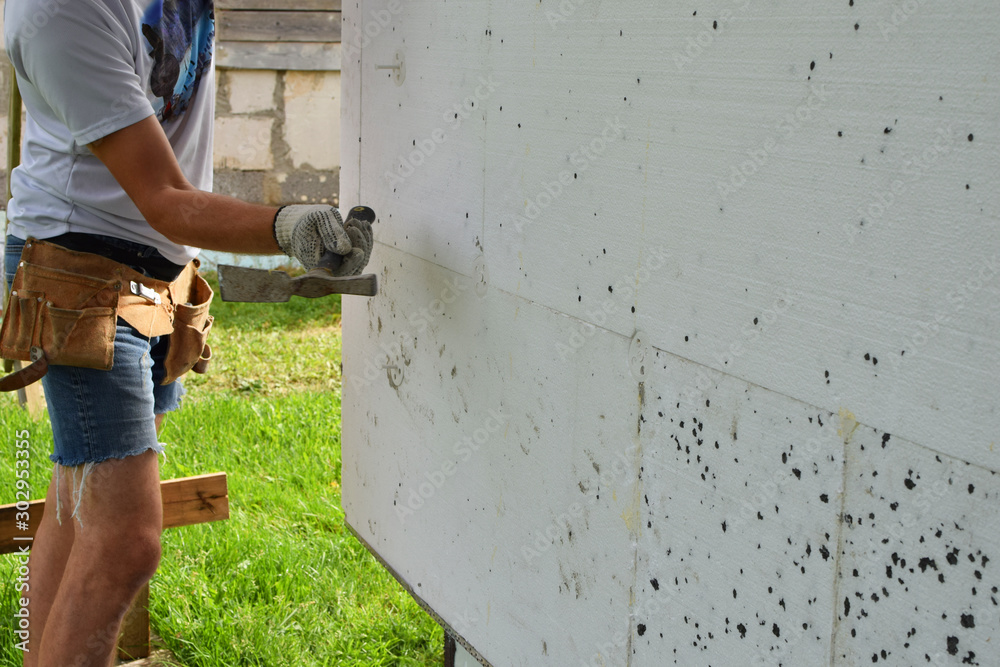 Constraction worker gloved hand using hammer to hammer white plastic ...