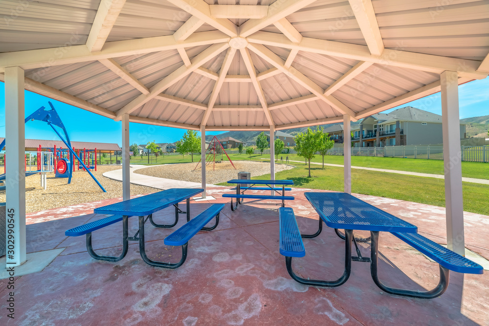 Blue picnic table and seats inside an octagon shape pavilion at a sunny ...