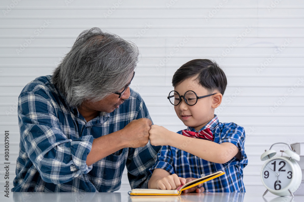 Happy asian senior retired grandfather teaching his grandson little boy ...