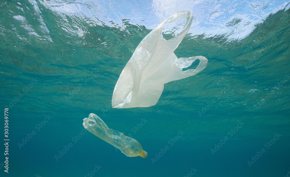 Underwater pollution, a plastic bag and a bottle adrift below water ...