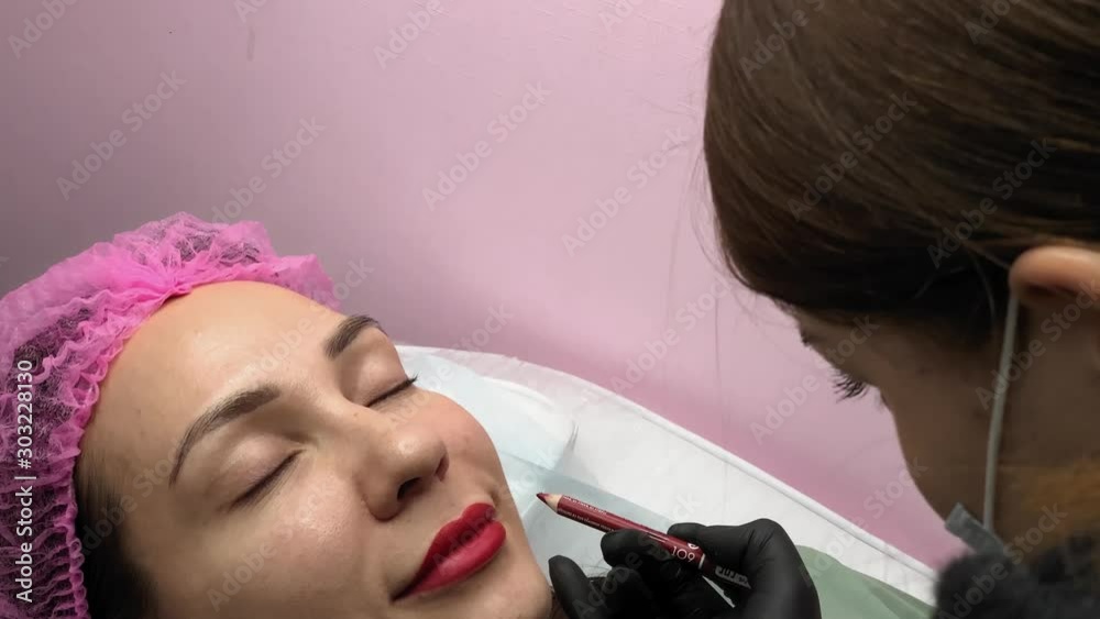 Preparation for permanent makeup. Draws a contour with a red pencil ...