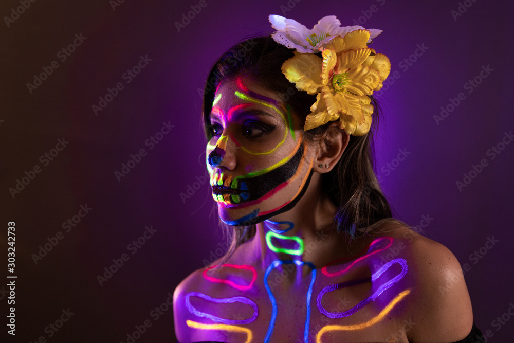 Retrato de joven maquillada de catrina con pintura neón iluminada con ...