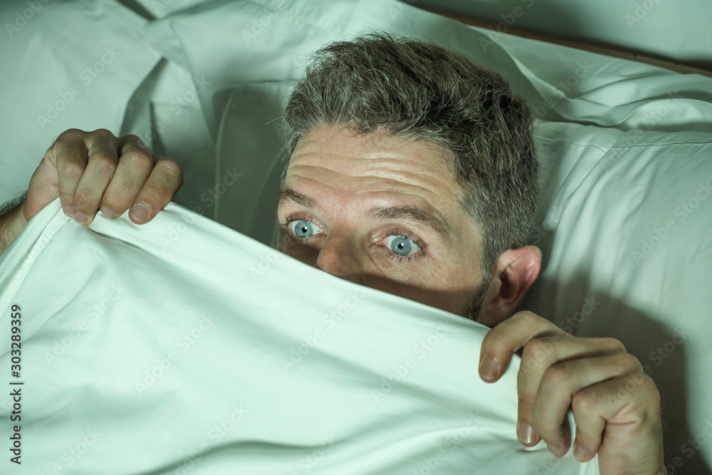 Foto de stressed and scared man alone in bed awake at night in fear ...