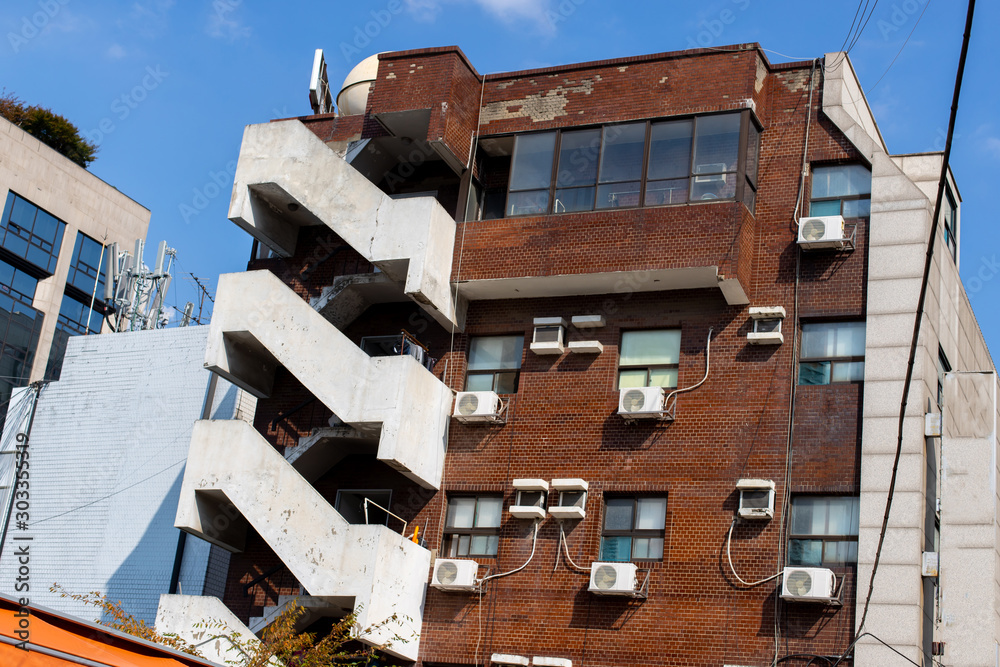 The dilapidated facade of multi-story building. Fire escape staircase ...