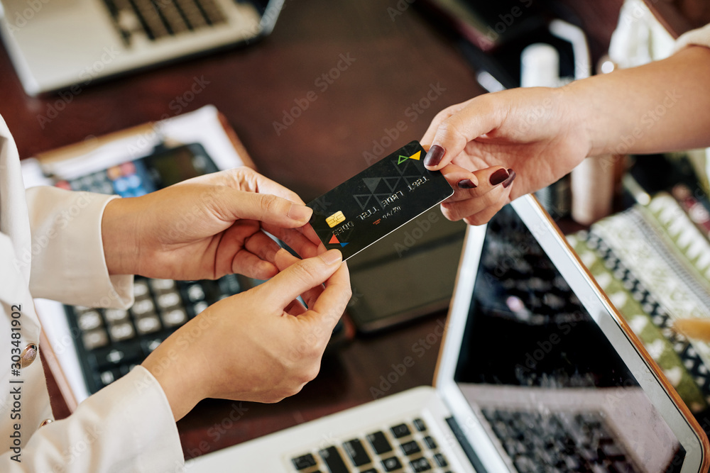 Hands of female client giving credit card to receptionist to pay for ...