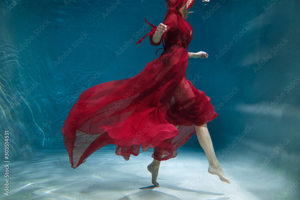 Female figure in a dark red dress underwater. Stock Photo | Adobe Stock