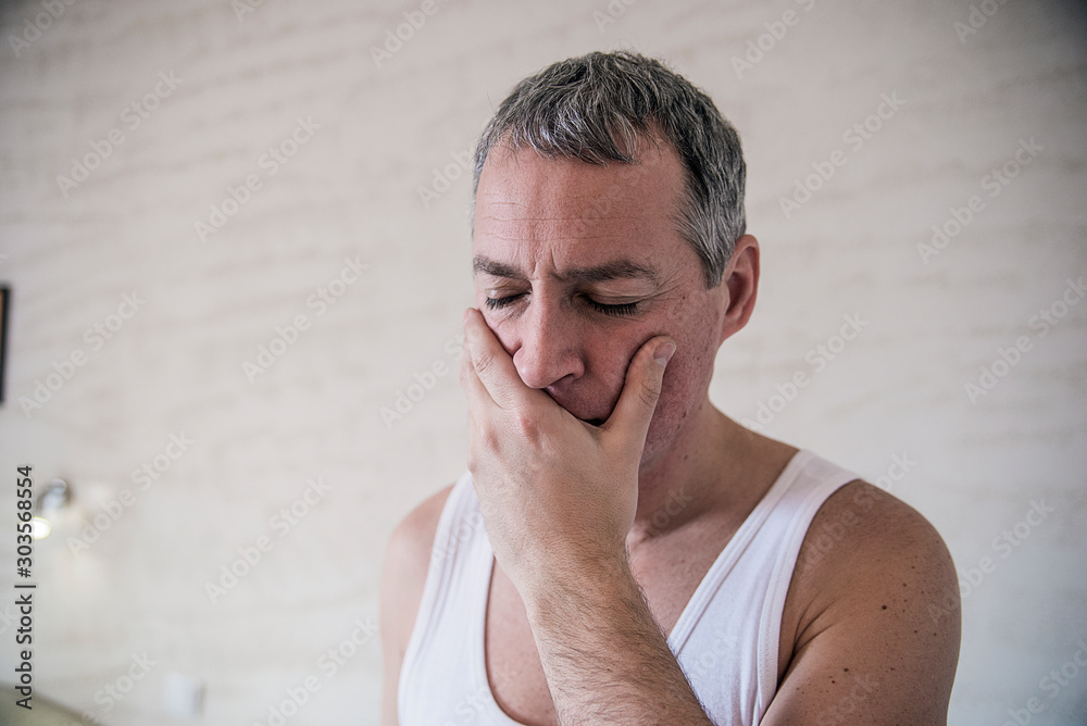 Toothache. Frustrated young man touching his cheek and keeping eyes ...