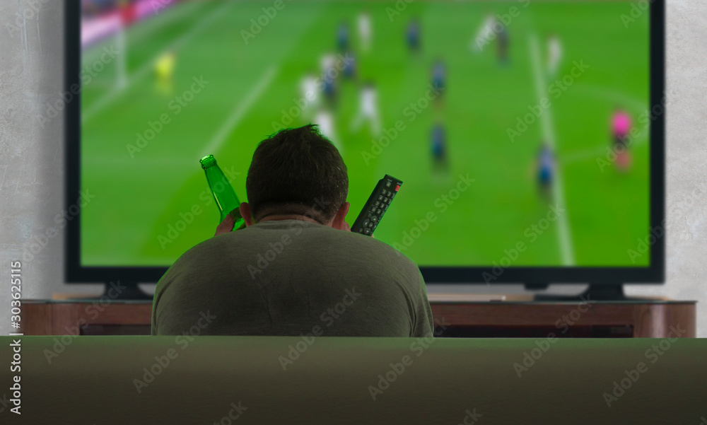 view from behind of young soccer fan man watching European football ...