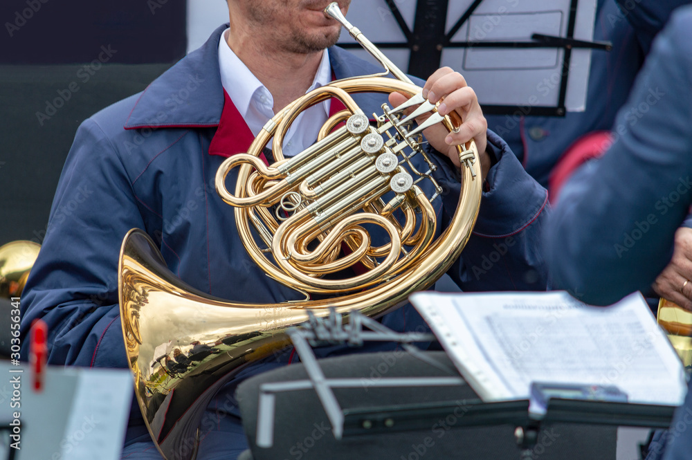Male musician plays horn (valtorna) musical instrument. Front view ...