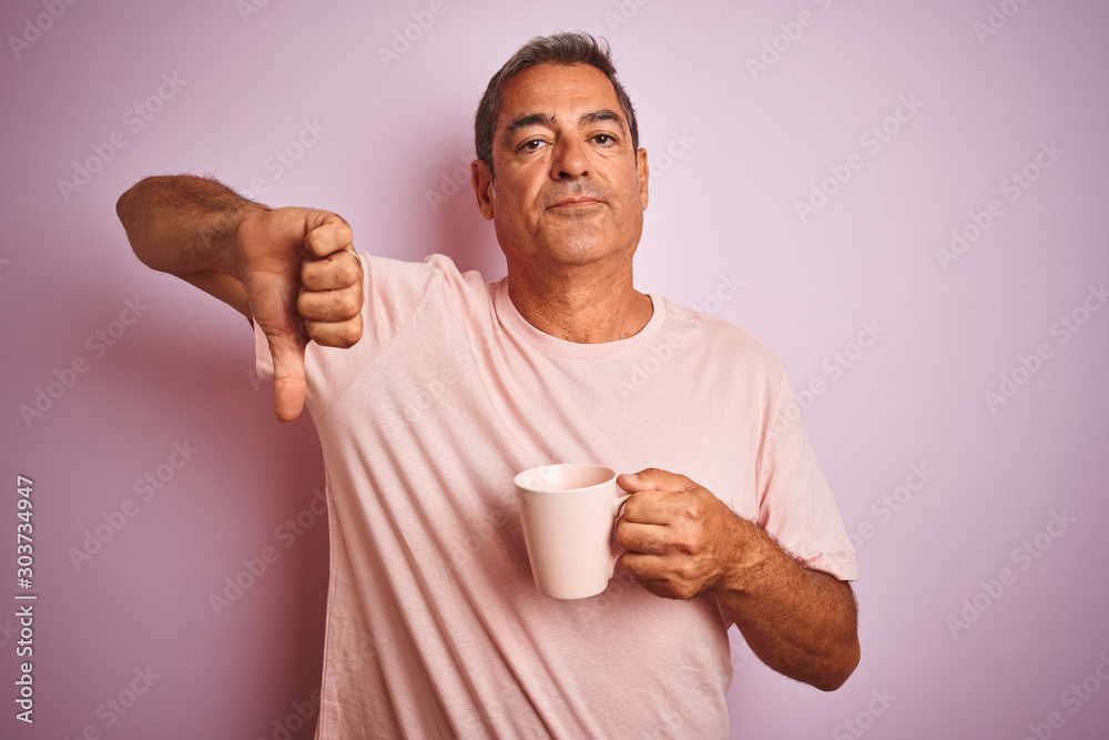 Handsome middle age man holding cup of coffee standing over isolated ...