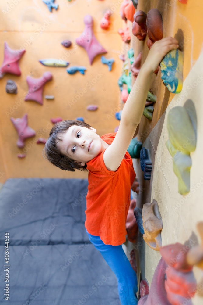 Boy climbing on artificial boulders wall in gym Stock Photo | Adobe Stock