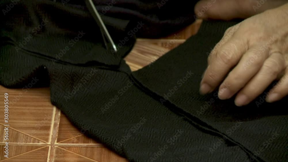 Someone has measured and is cutting open a garment using scissors ...