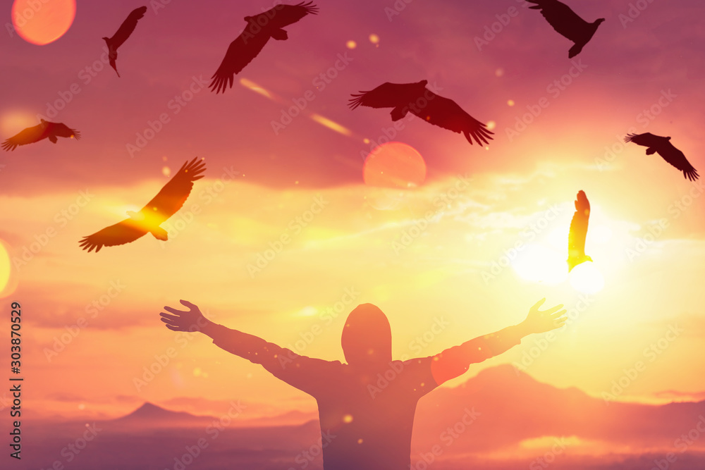 Man raise hand up on top of mountain and sunset sky with eagle birds ...
