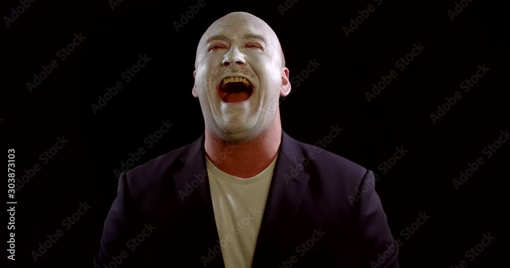 man with white makeup on face is laughing like a joker in black ...