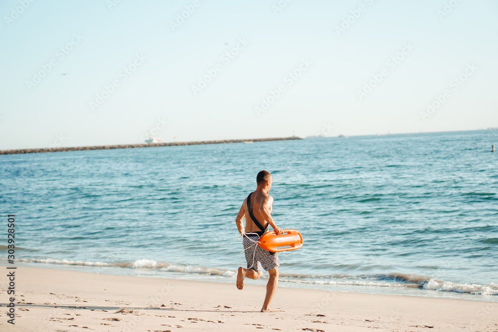 Male lifeguard running on the beach. Stock Photo | Adobe Stock