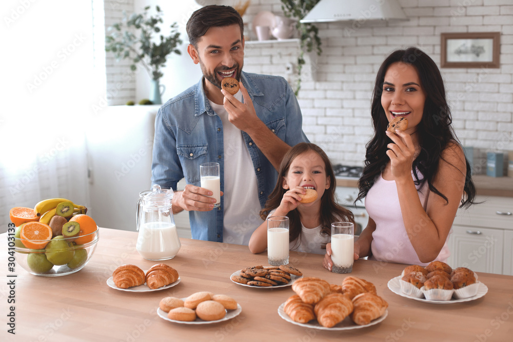 portrait of happy family eating cookies with milk and looking at the ...