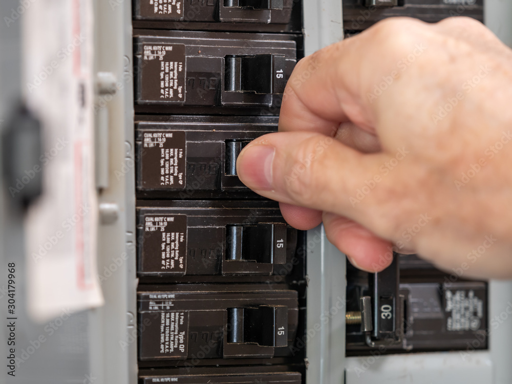 Male electrician turning off power for electrical outlet at circuit ...