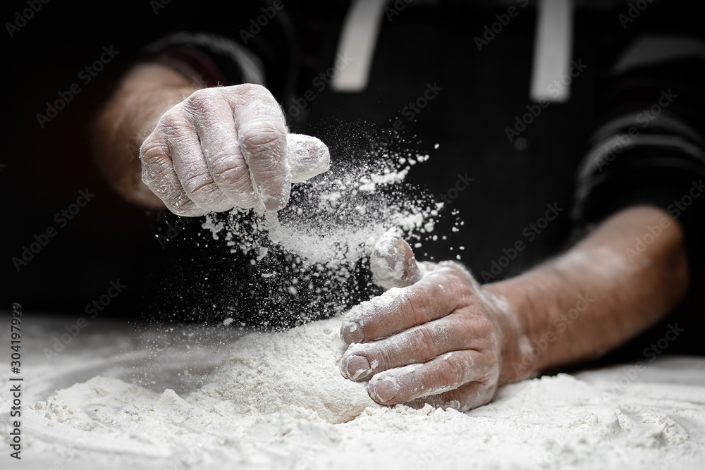 Poster, Foto White flour flies in air on black background, pastry chef ...