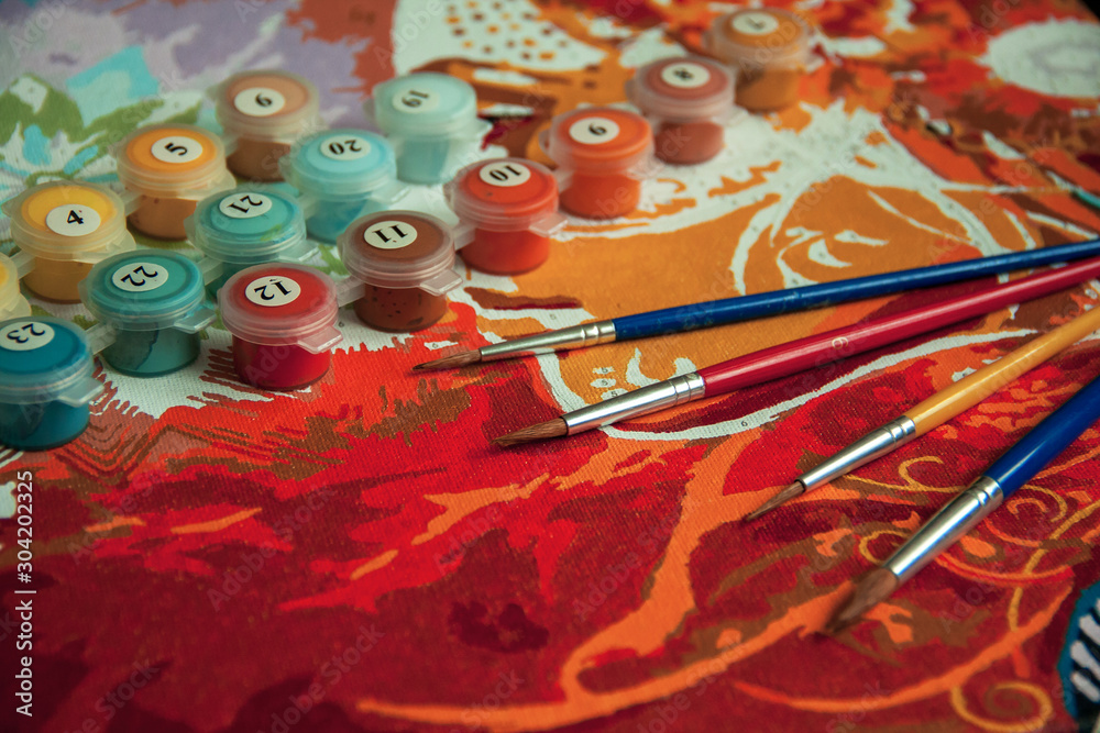 Number painting brushes and colors set on a canvas in process of ...