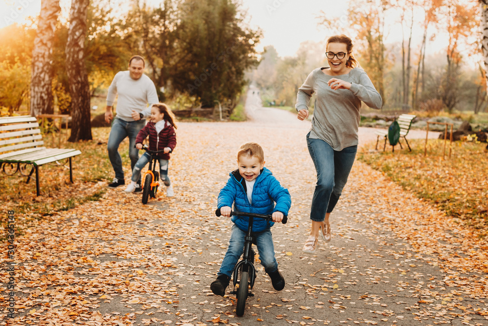 Cute little kid riding ahead with his bicycles while his mother is ...