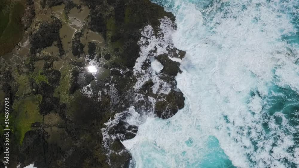 Aerial shot of large surging sea waves at medium tide from the teal ...