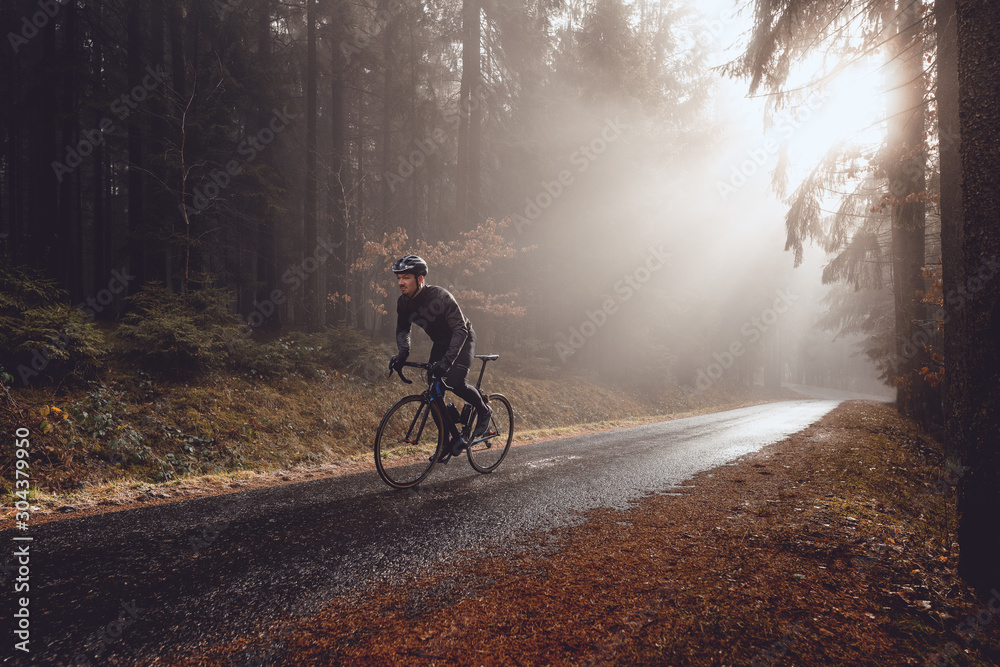Rennradfahrer im Wald bei herbstlichem Wetter mit Sonnenstrahlen im ...