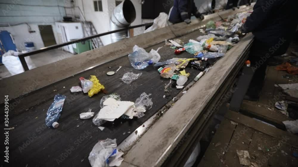 Workers sorting garbage on moving conveyor belt at recycling plant for ...