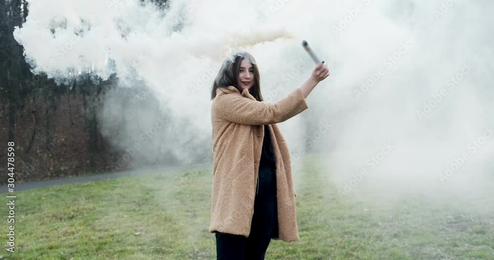 Woman makes emergency flare signal with white smoke. Hipster pretty ...