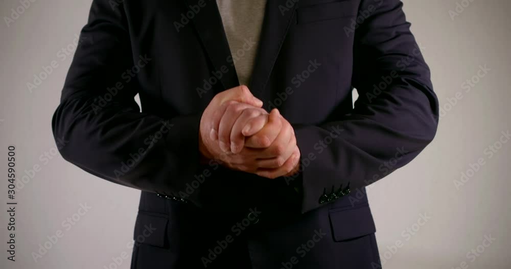 the middle plan of the male body in a dark suit. the man folds his ...