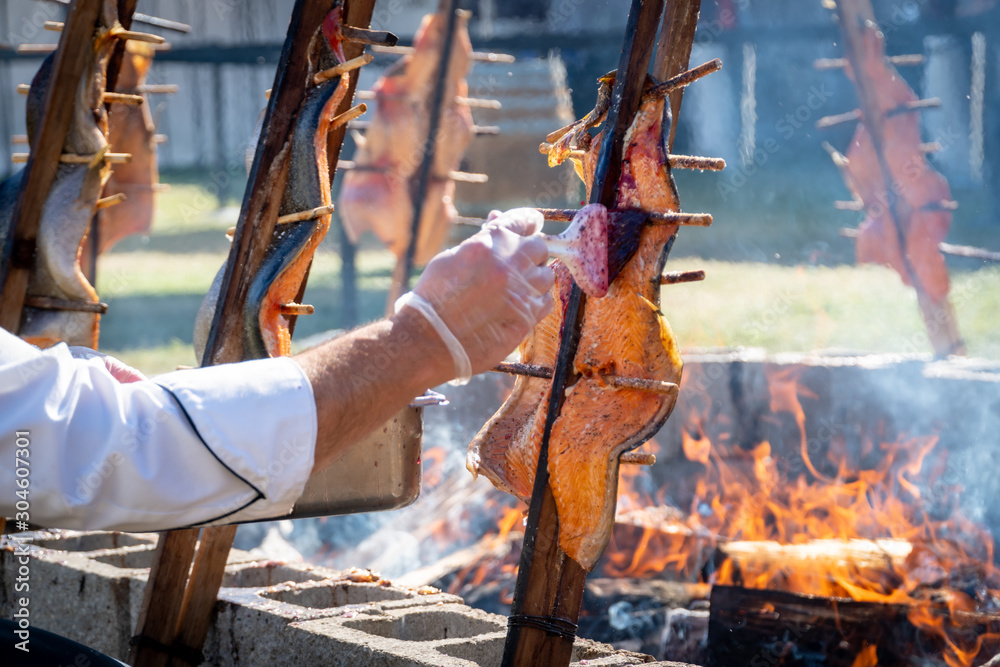 Salmon being grilled over an open fire using a traditional native ...