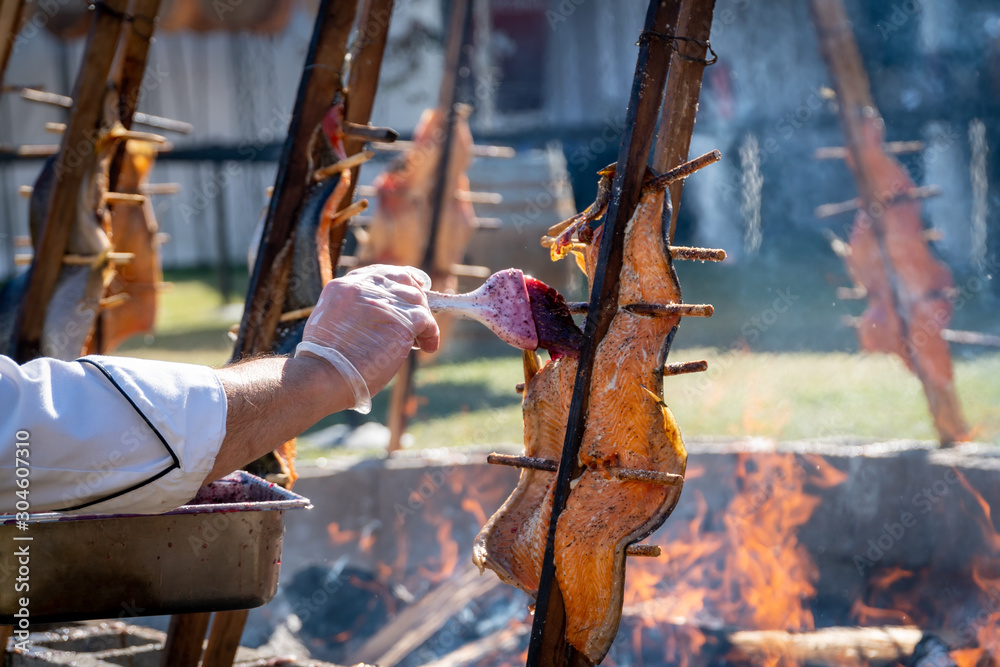 Salmon being grilled over an open fire using a traditional native ...