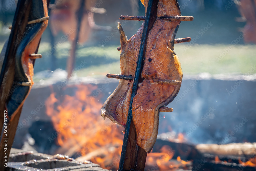 Salmon being grilled over an open fire using a traditional native ...