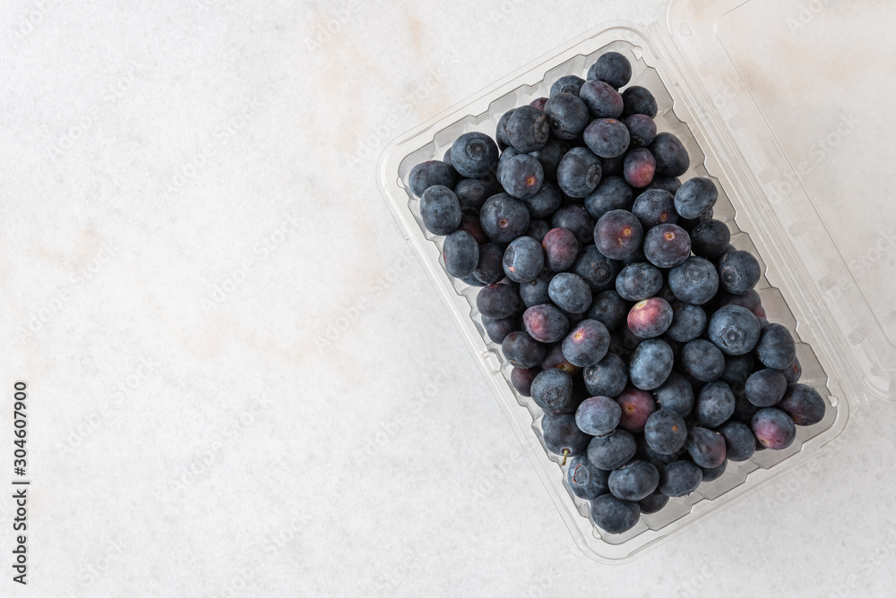 Open clamshell container of blueberries on a white granite counter ...