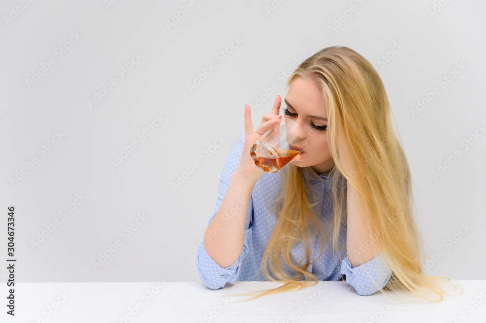 Concept woman with alcohol problems sits at a table with whiskey in a ...