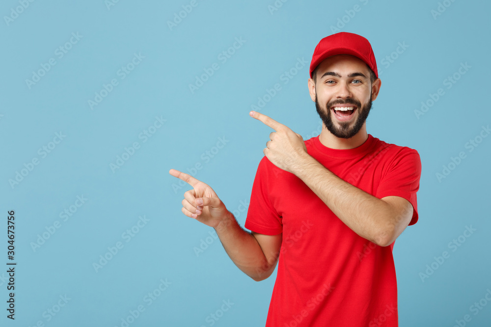 Delivery man in red uniform workwear isolated on blue wall background ...